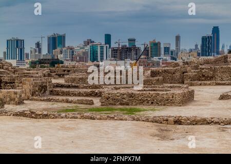 Ruins of Bahrain Fort with skyline of Manama. A UNESCO World Heritage ...