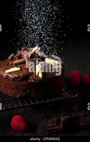 Icing sugar falling onto chocolate gateau Stock Photo - Alamy