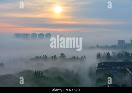 The sun is about to rise between thick fog and the colored sky over ...
