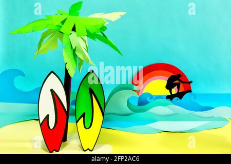Creative papercraft of a beach, surfboards and a surfer silhouette on ...