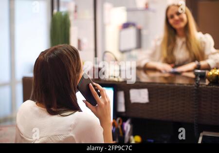 Beauty salon receptionist with notebook at desk Stock Photo - Alamy