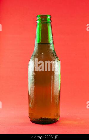 A glass mug containing an amber liquid sits on a dark surface ...