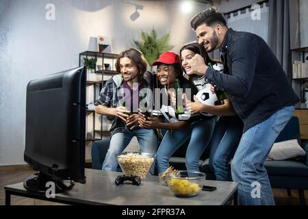 Friends cheering. Four happy soccer fans drinking beer at the pub Stock ...