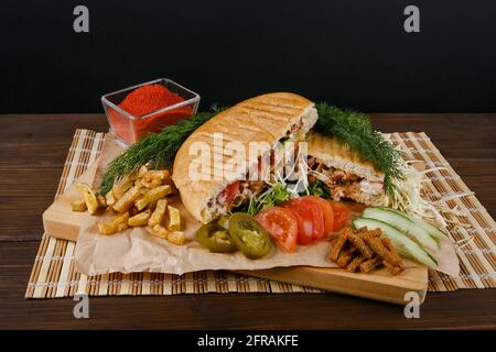 Fresh hot fragrant shawarma cut lies on a wooden board with vegetables ...