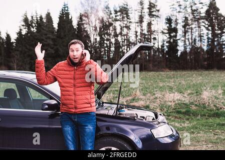 Man calling repair service after car breakdown.youg man talking on cell ...
