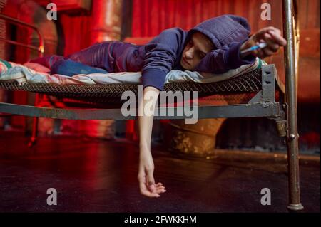 Drug addict woman sleeps on bed in den, shebang interior on background ...