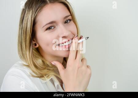 Portrait of smiling blond woman smoking cigarette Stock Photo - Alamy
