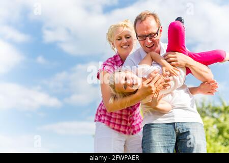 Family romping on field with parents carrying child Stock Photo - Alamy