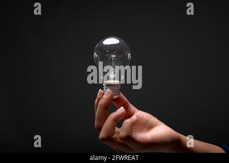 Mid section of businesswoman holding a light bulb using laptop against ...