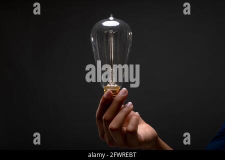 Mid section of businesswoman holding a light bulb against black ...