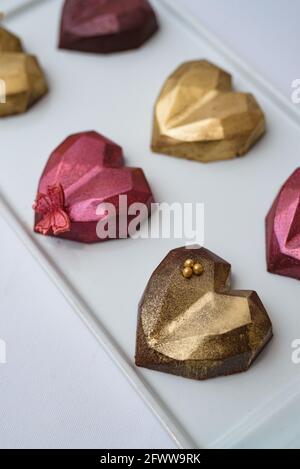 Heart-shaped plate with chocolate candies, bottle of wine and rose ...