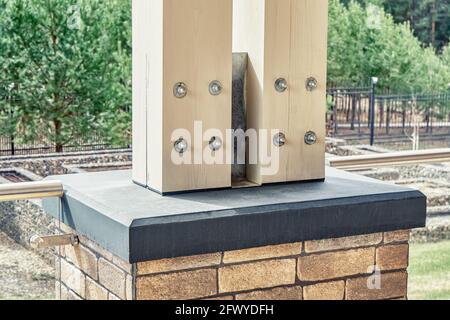 Support of wooden poles for roof overhanging above terrace on concrete ...