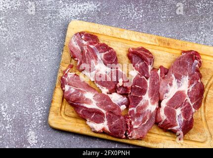 Raw blade steak from pork shoulder in a white plate on a dark wooden ...