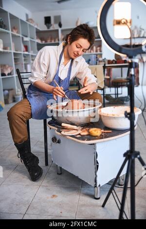 Craftsman taking clay bowl off pottery wheel. Complete handmade ...