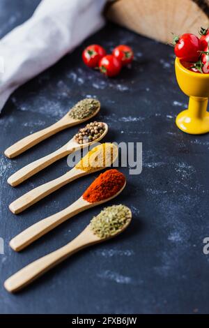 Wooden spoons with spices, paprika, basilic, pepper, thyme with cherry ...