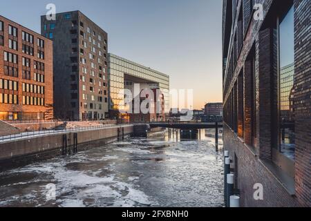 Germany, Hamburg, Frozen waters of Brooktorhafen at dusk in winter ...