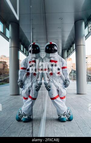 Man, astronaut standing on reflection surface with fog and graphic sky ...