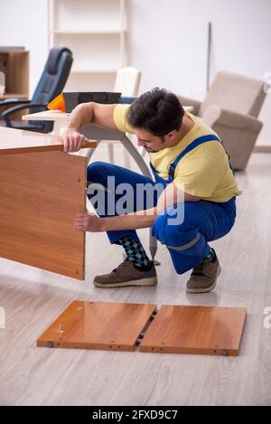 Young carpenter repairing desk in the office Stock Photo - Alamy