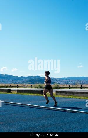 Back view of a young female sprinter running on an athletics track ...