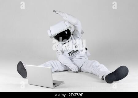 Astronaut stretching while looking at the laptop, white background ...