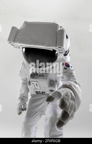 Astronaut stretching hand, white background Stock Photo - Alamy