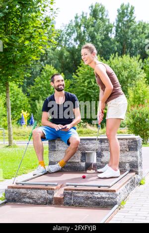 Caucasian couple playing miniature golf Stock Photo - Alamy