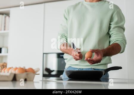 cropped view of man frying chicken egg with fire on frying pan Stock ...