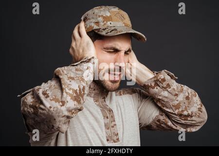 Unhappy masculine military man with headache rubbing his temples ...