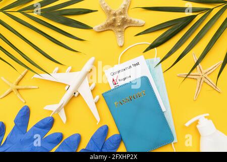 Toy plane, passport and coronavirus test results on yellow background ...
