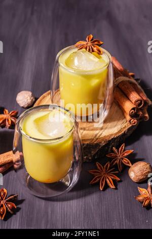 Golden turmeric milk with ice. Cinnamon, nutmeg, anise spices. Trendy ...