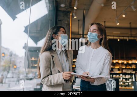 two businesswomen with their face masks debating different views on ...