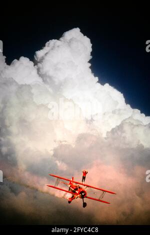 Vintage biplane aircraft flying through dramatic storm clouds at air ...