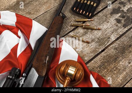 Wooden judge gavel and hunting rifle over USA flag on wooden background ...