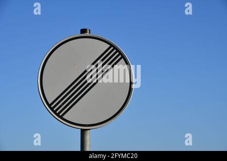 german round traffic sign repealing any speed limit in front of blue ...