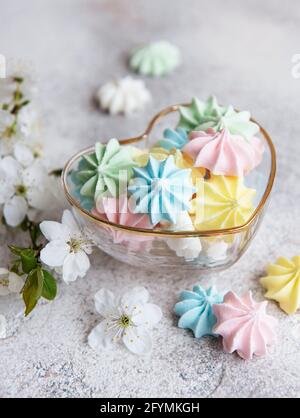 Small colorful meringues in the heart shaped bowl on concrete ...