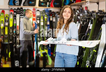Woman shopper choosing new skis in shop of sports equipment Stock Photo ...