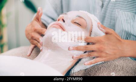 Cosmetologist applying rejuvenating facial mask on a female face in ...