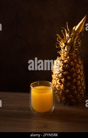 Pineapple fruit and juice in double glass cup on white stone background ...