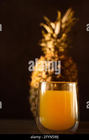 Pineapple fruit and juice in double glass cup on white stone background ...