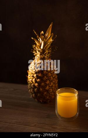 Pineapple fruit and juice in double glass cup on white stone background ...