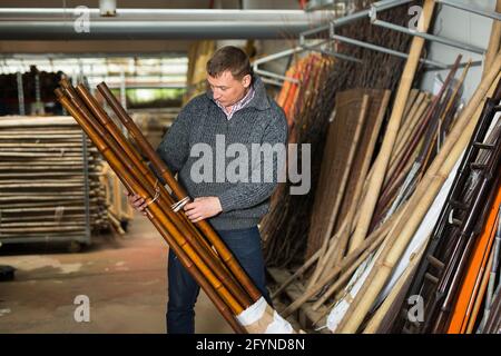 Young man choosing bamboo stakes at garden material store Stock Photo ...