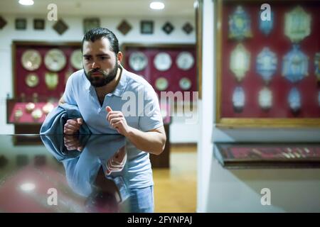 Attentive adult man exploring artworks in glass case in museum Stock ...
