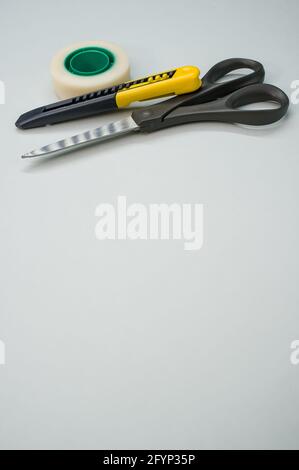 Closeup shot of scissors adhesive tape and a utility knife on an orange ...