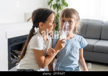 Asthma spacer. Young girl using a spacer (plastic chamber) with an ...
