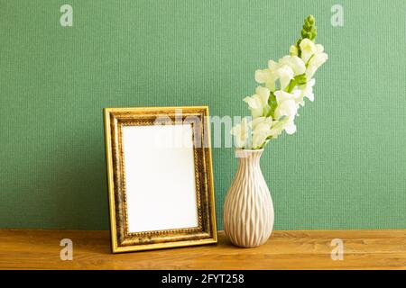 Empty photo frame with snapdragon flowers on wooden table. orange ...