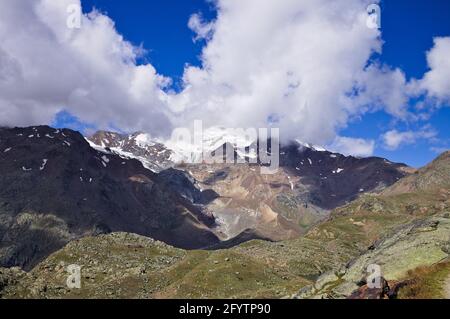 Big clouds above snow capped peaks of mountains in the italian Alps ...