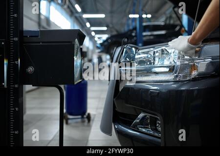 Male mechanic adjusts the headlights, car service. Vehicle repairing ...
