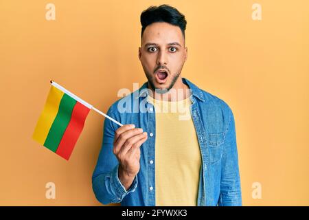Young arab man holding lithuania flag smiling with an idea or question ...