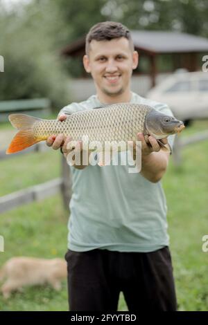 Happy angler holds trophy carp. Man with carp fish. Outdoors activities ...