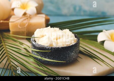 Bowl with shea butter, soap and palm leaves on color background Stock ...